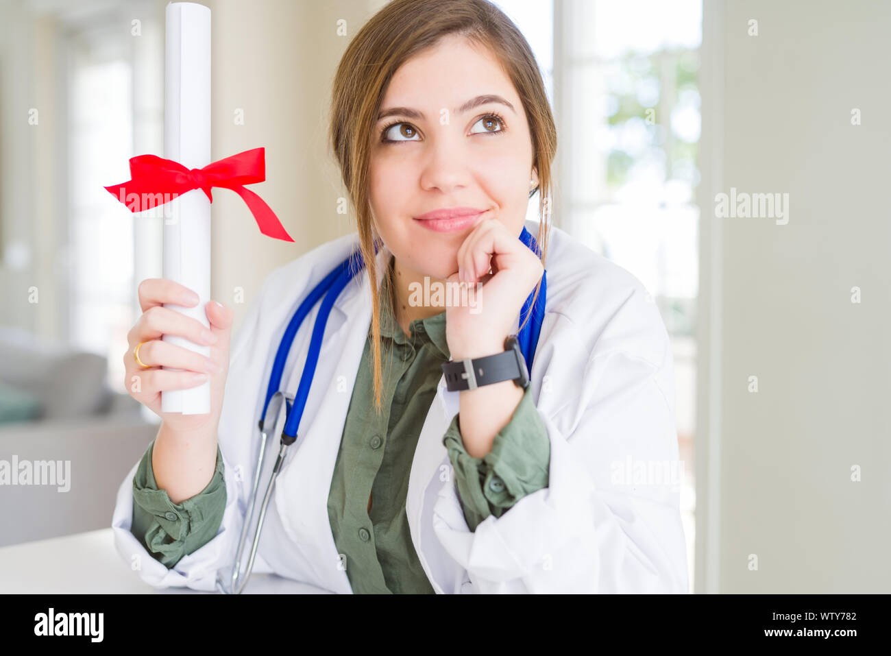 Beautiful young doctor woman holding degree serious face thinking about ...