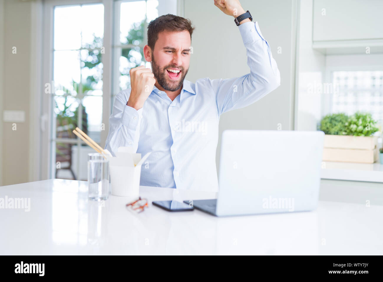 Business man eating take away asian noodles food while working using ...
