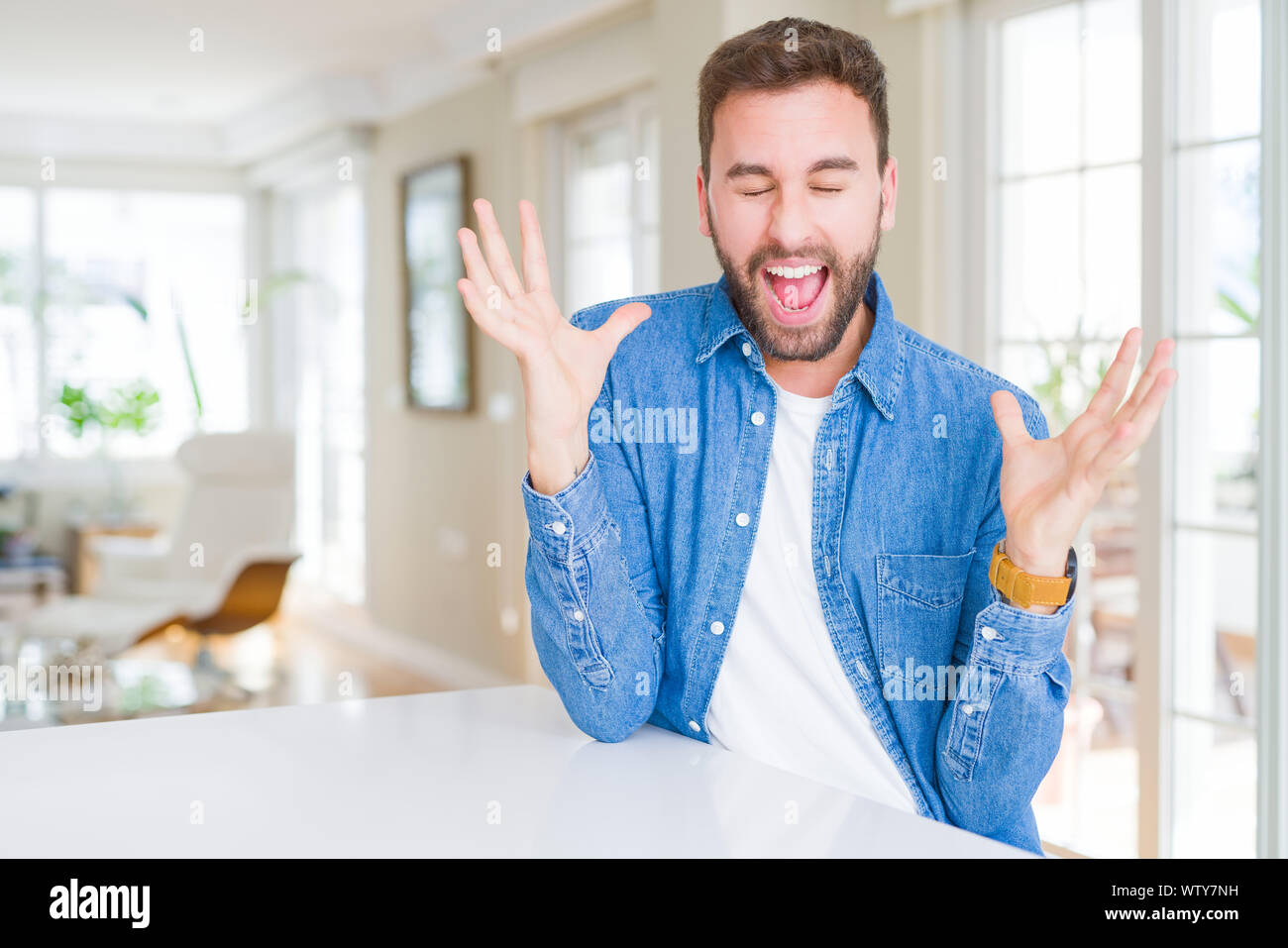Handsome man at home celebrating mad and crazy for success with arms ...