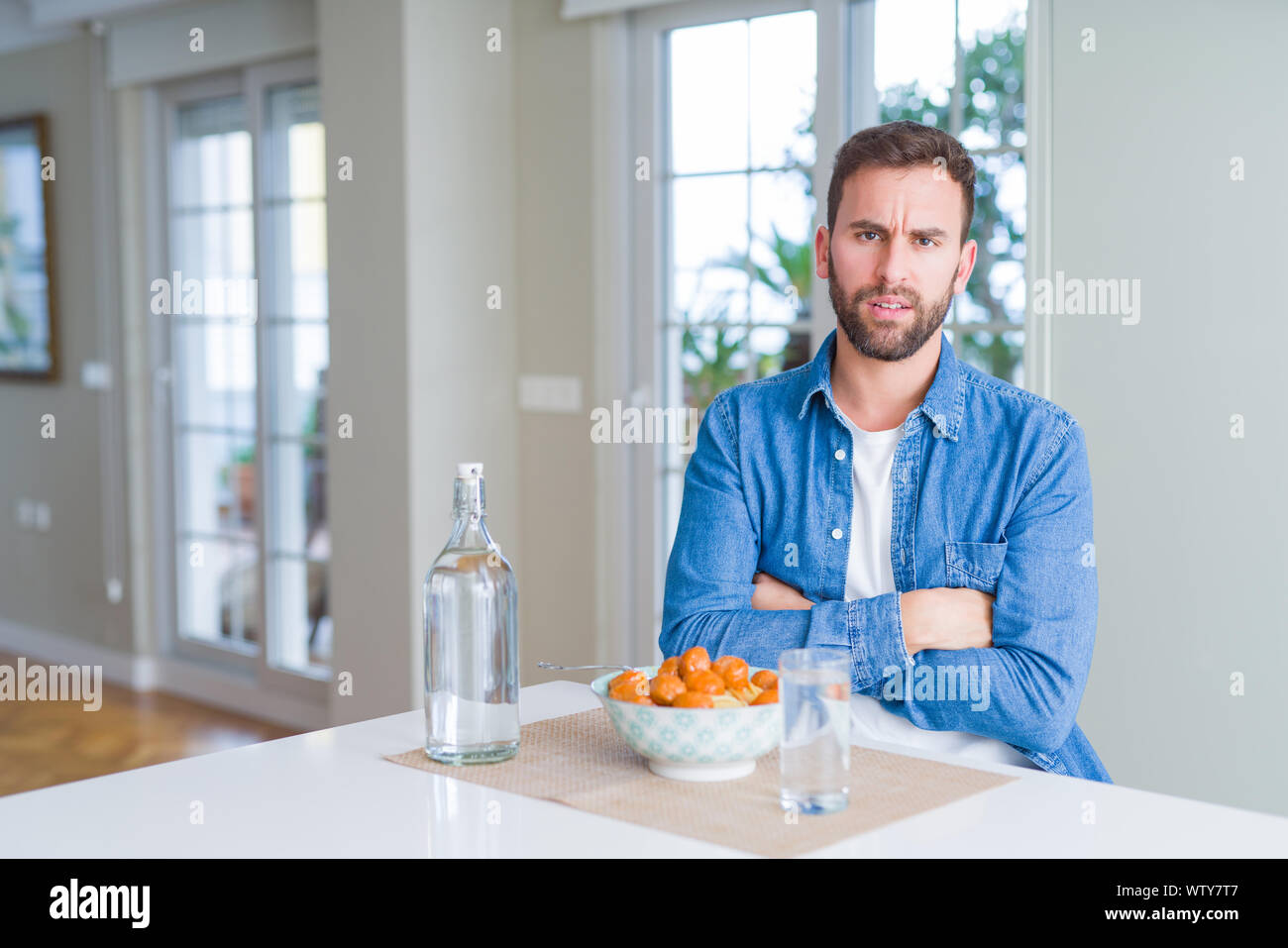 Handsome man eating pasta with meatballs and tomato sauce at home ...