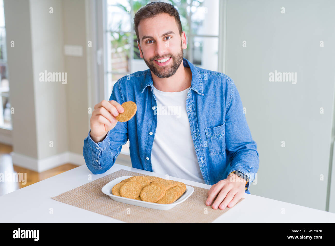 Handsome man eating healthy whole grain biscuit with a happy face ...