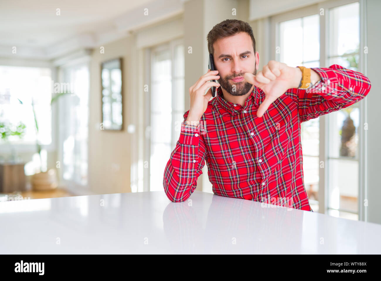 Handsome man talking on smartphone with angry face, negative sign ...