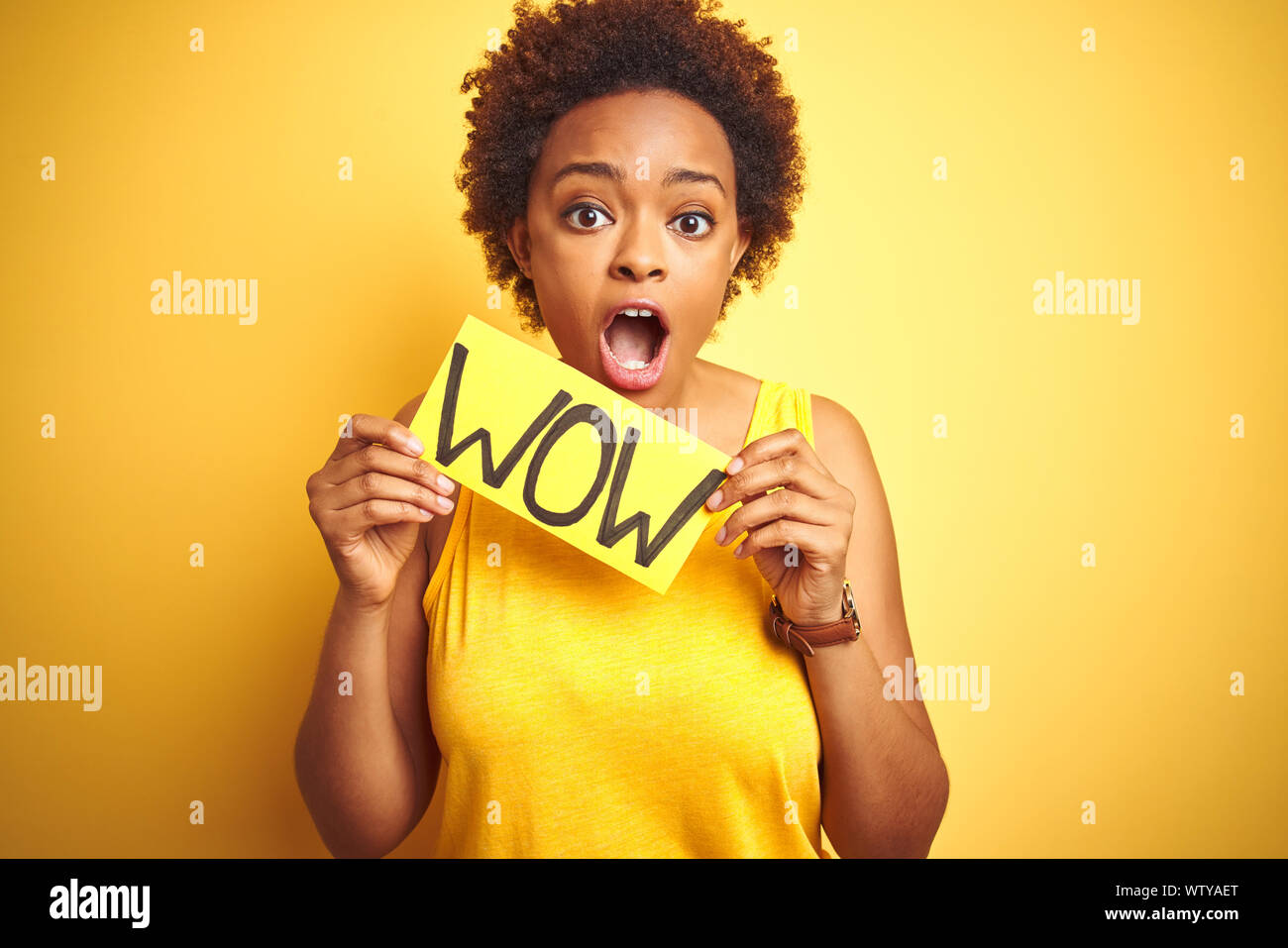 Young african american woman showing wow banner board over yellow ...