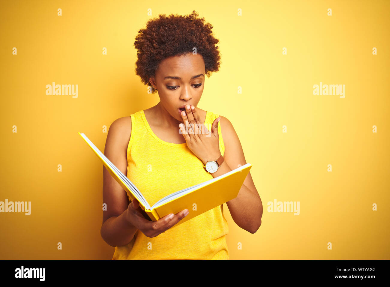 African american woman reading a book over yellow isolated background ...