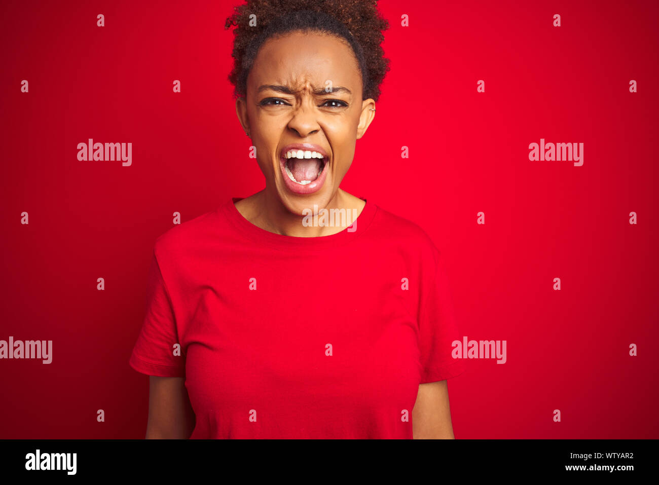 Young beautiful african american woman with afro hair over isolated red ...