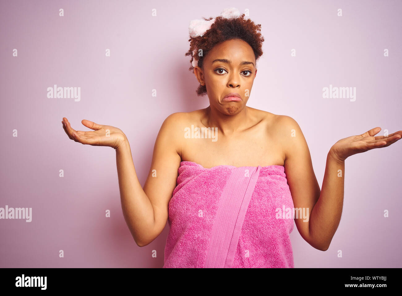 African american woman wearing shower towel after bath over pink ...