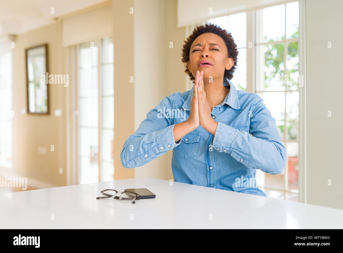 Young beautiful african american woman begging and praying with hands ...