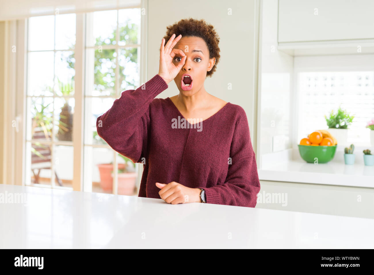 Young beautiful african american woman at home doing ok gesture shocked ...