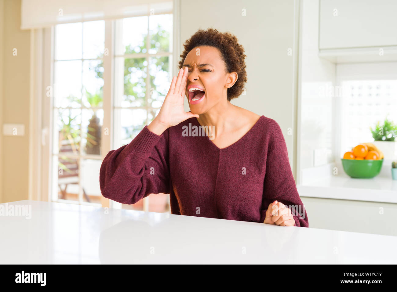 Young beautiful african american woman at home shouting and screaming ...