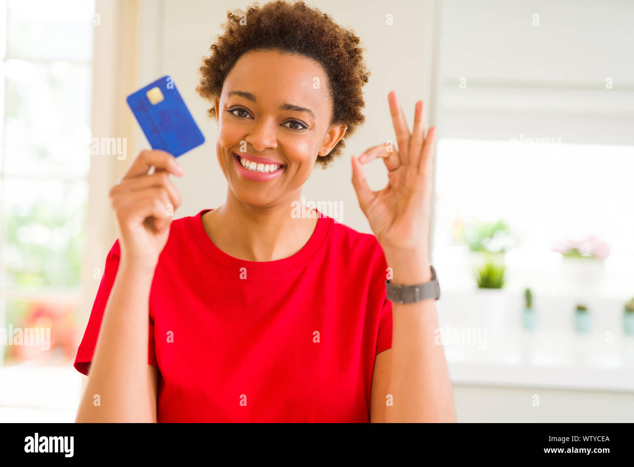 Young african american woman holding credit card doing ok sign with ...