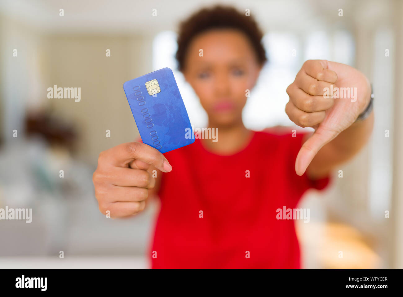 Young african american woman holding credit card with angry face ...