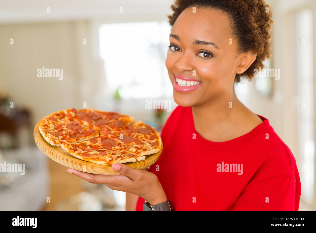 Beautiful young african american woman showing homemade tasty pizza ...