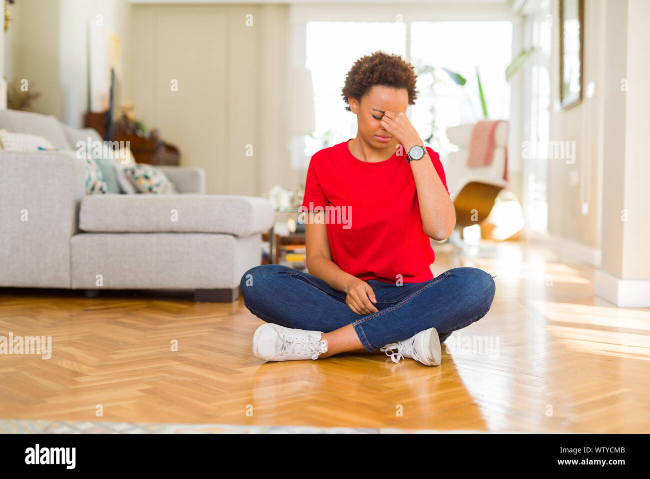 Young beautiful african american woman sitting on the floor at home ...