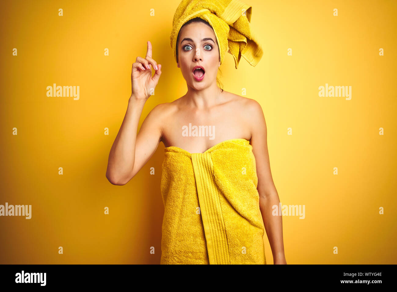 Beautiful woman wearing shower towel on body and head over yellow ...