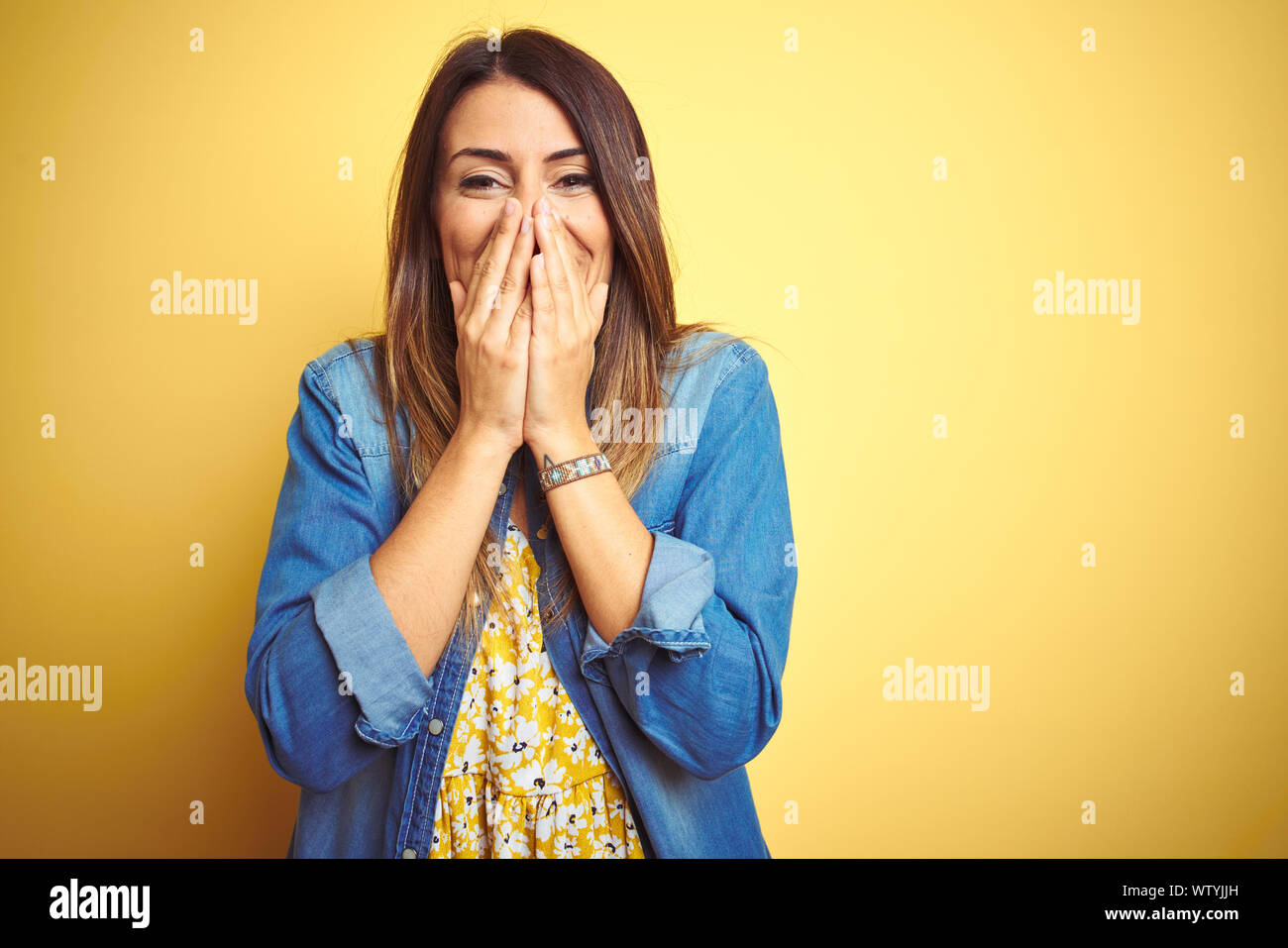 Young beautiful woman standing over yellow isolated background laughing ...