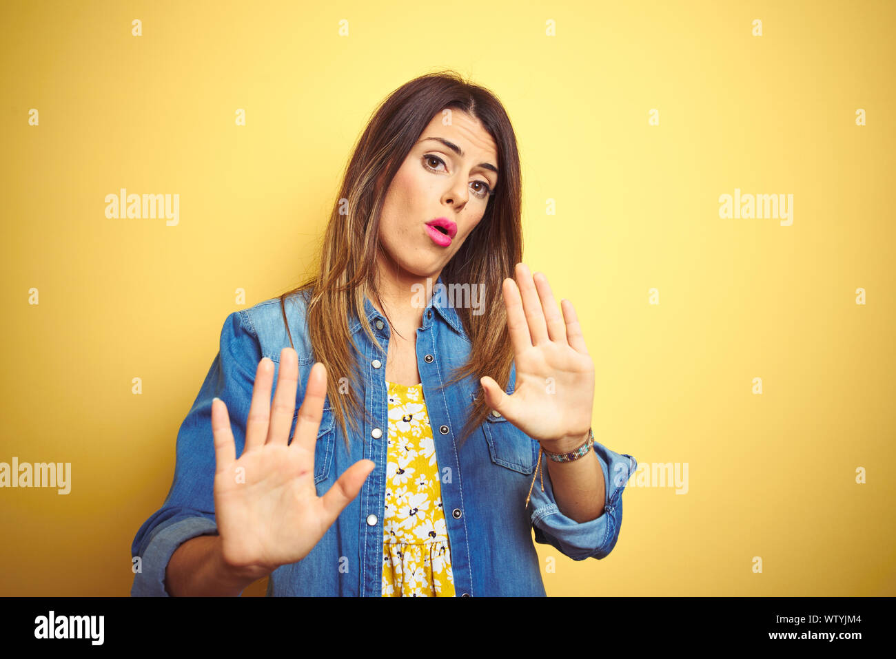 Young beautiful woman standing over yellow isolated background Moving ...