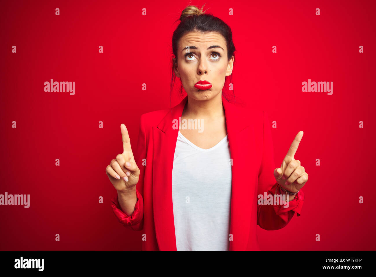 Young beautiful business woman standing over red isolated background ...