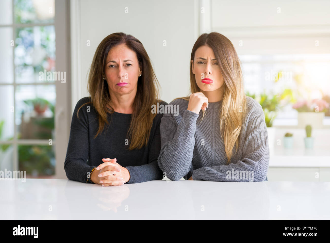 Beautiful family of mother and daughter together at home depressed and ...