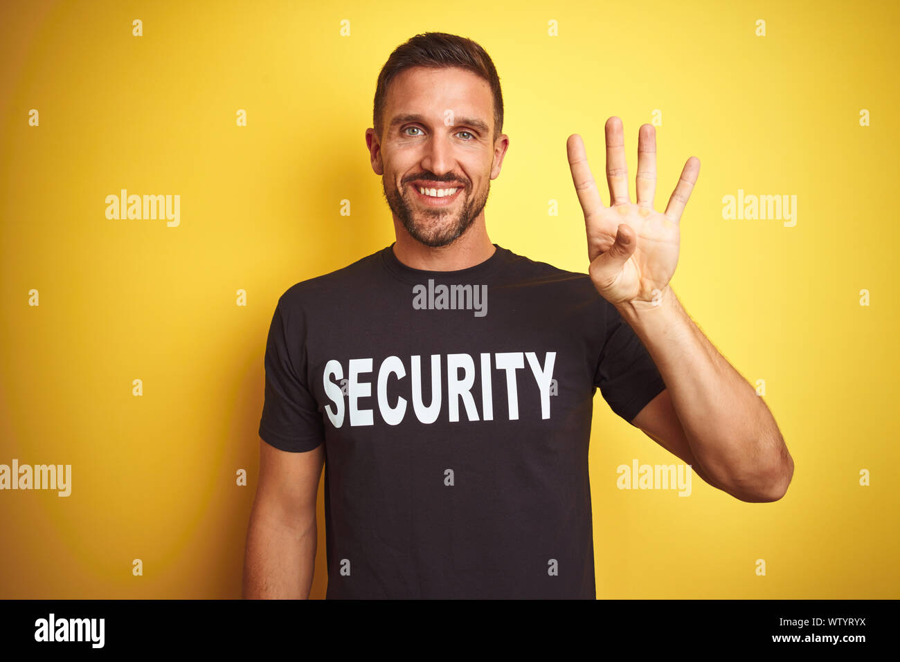 Young safeguard man wearing security uniform over yellow isolated ...