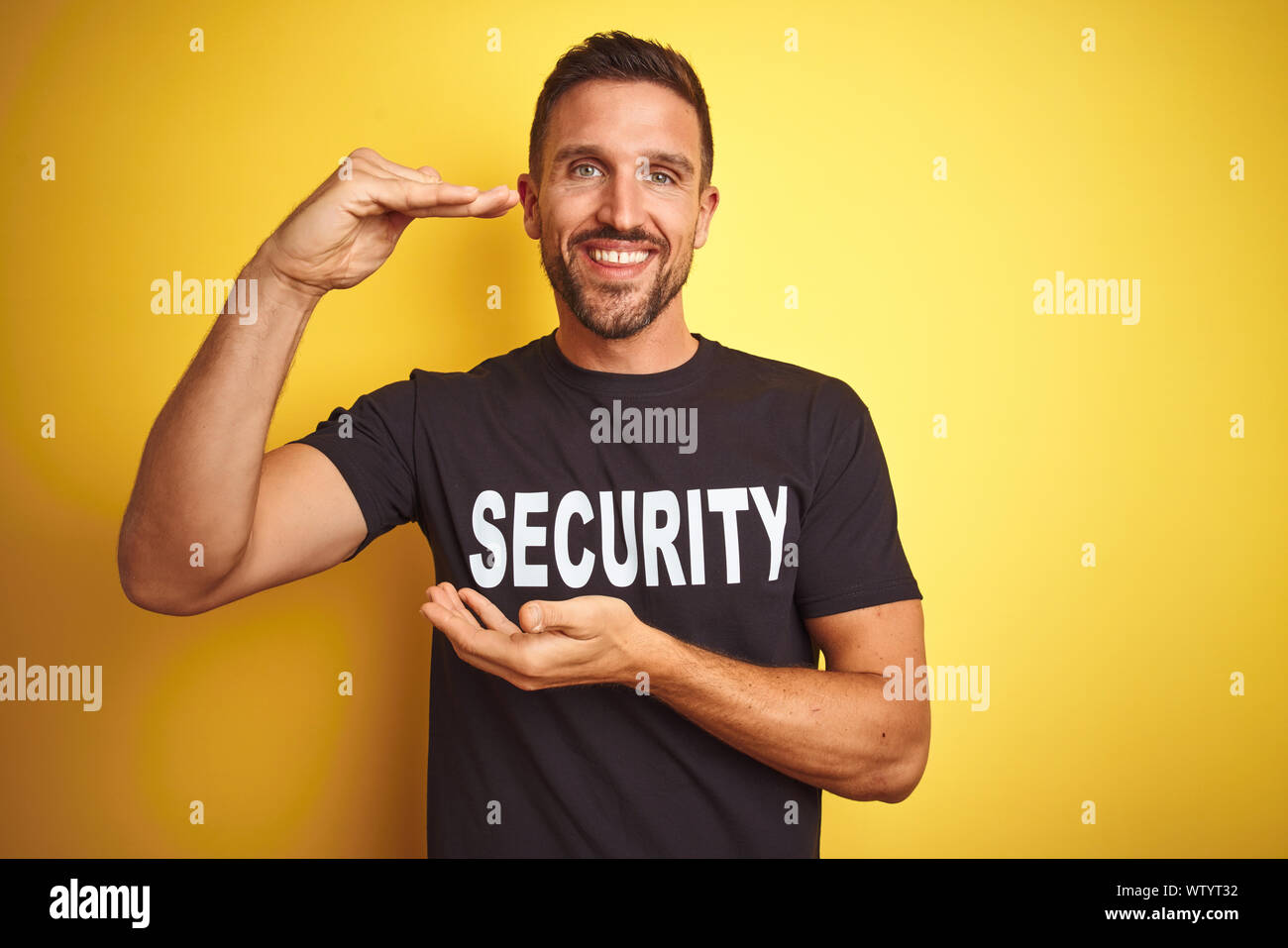 Young safeguard man wearing security uniform over yellow isolated ...