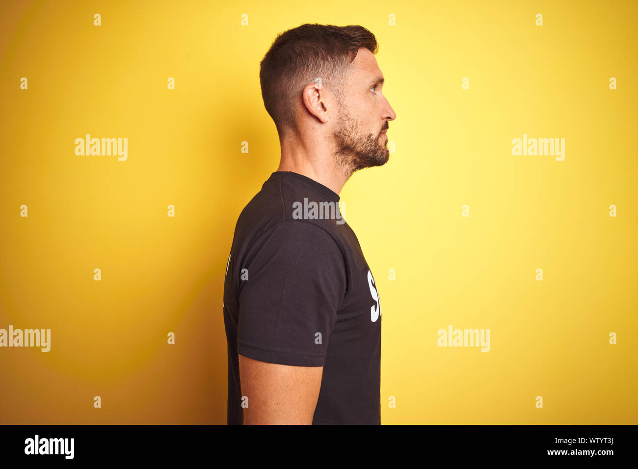 Young safeguard man wearing security uniform over yellow isolated ...