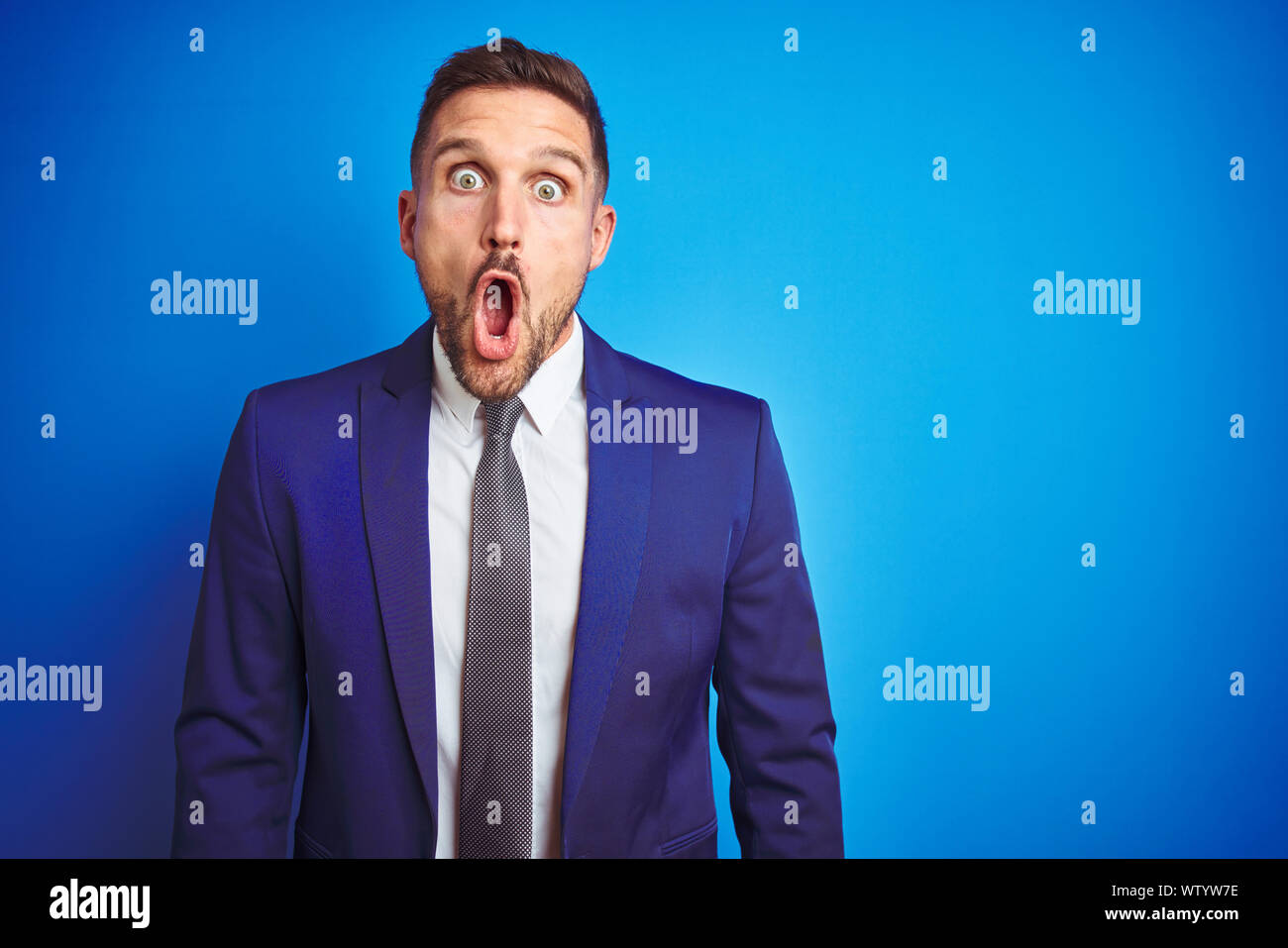 Young handsome business man over blue isolated background afraid and ...