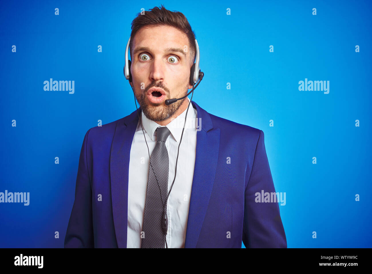 Young handsome operator man wearing call center headset over blue ...