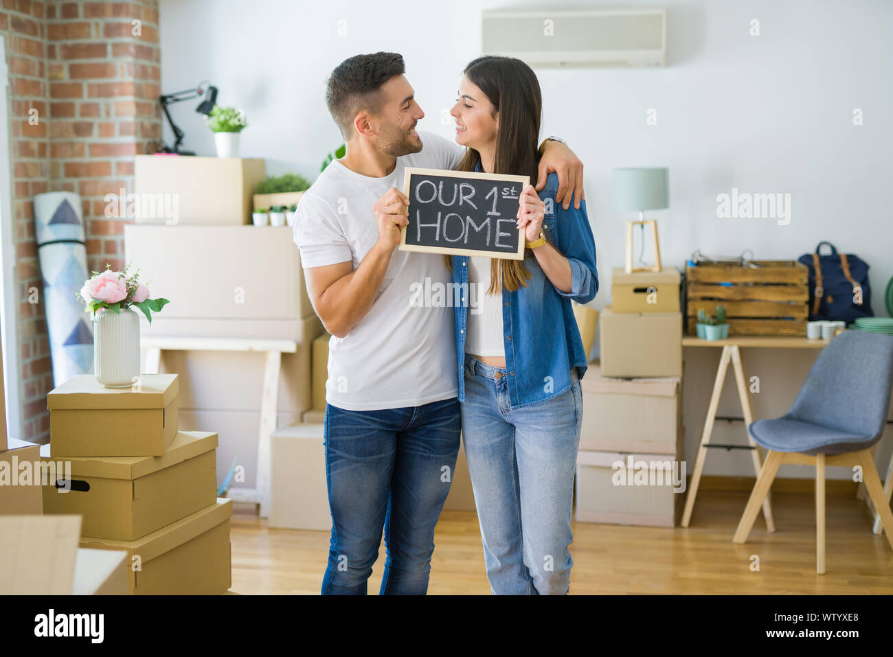 Beautiful young couple moving to a new house, smiling very happy ...