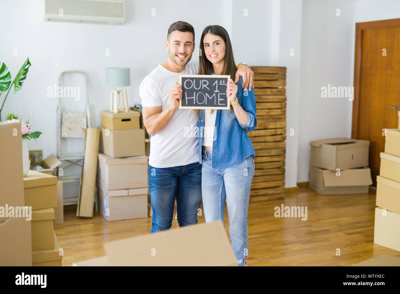 Beautiful young couple moving to a new house, smiling very happy ...