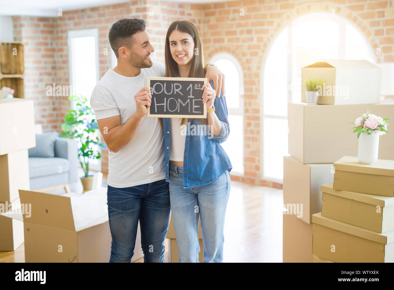 Beautiful young couple moving to a new house, smiling very happy ...