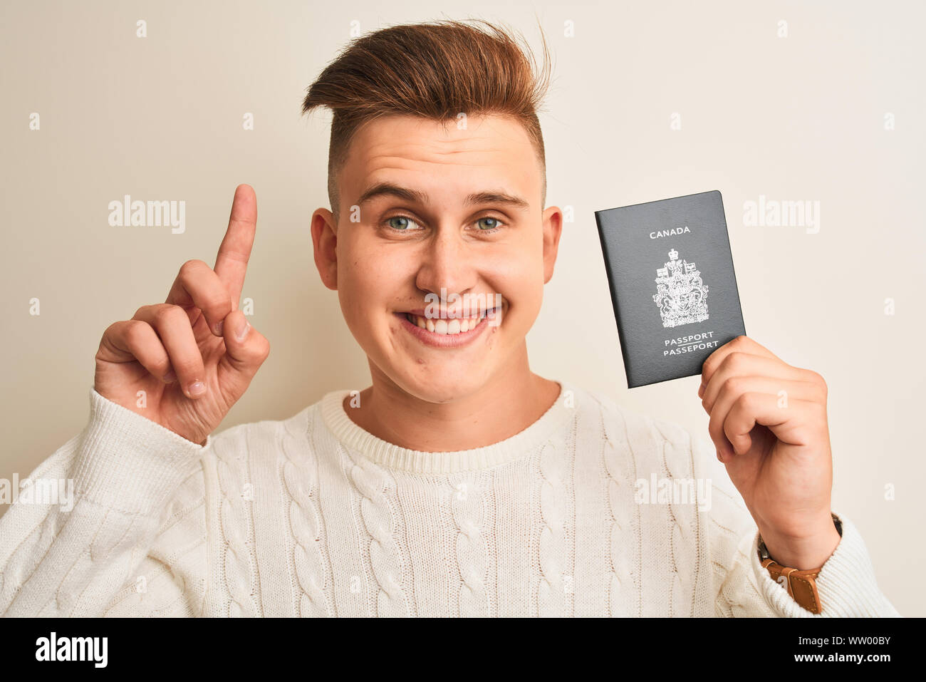 Young handsome man holding Canada Canadian passport over isolated white ...
