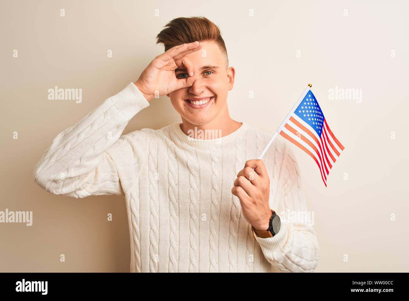 Young handsome man holding USA flag over isolated white background with ...