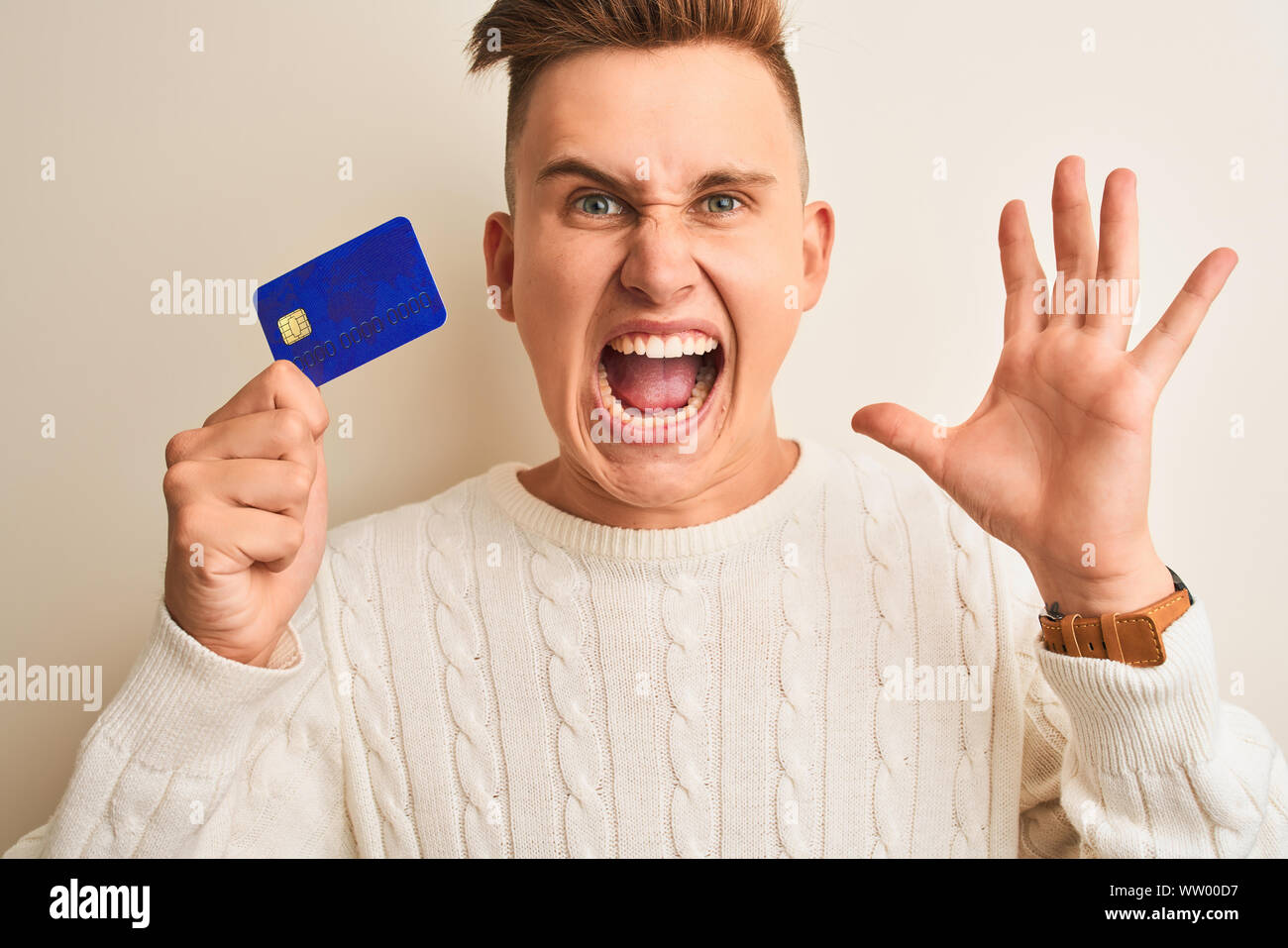 Young handsome man holding credit card over isolated white background ...