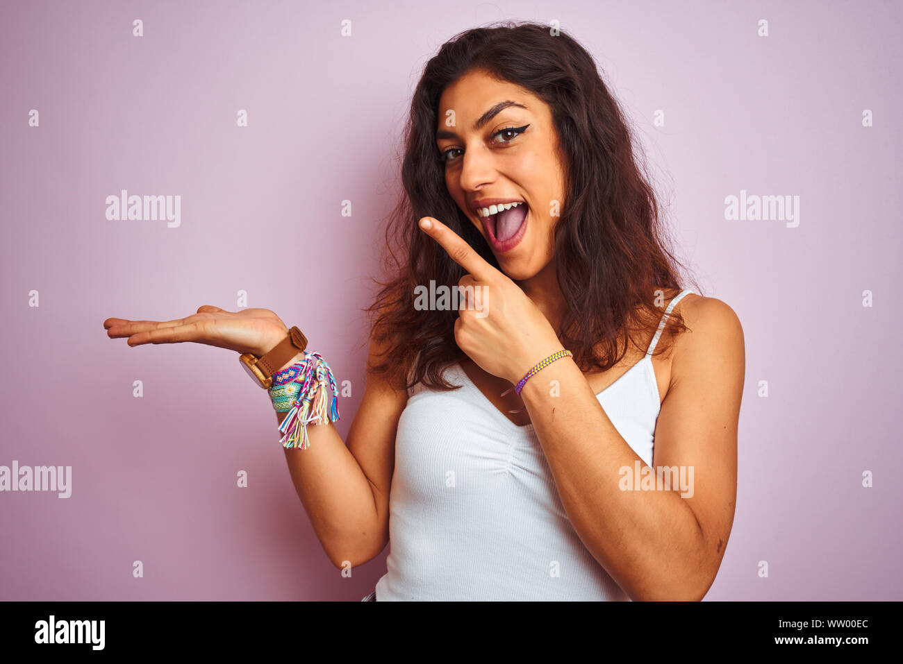Young beautiful woman wearing white t-shirt standing over isolated pink ...