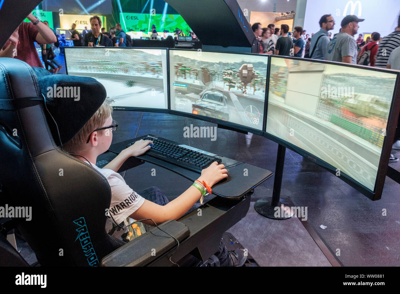 youn boy plays car racing game on multiple screens in driving simulator ...