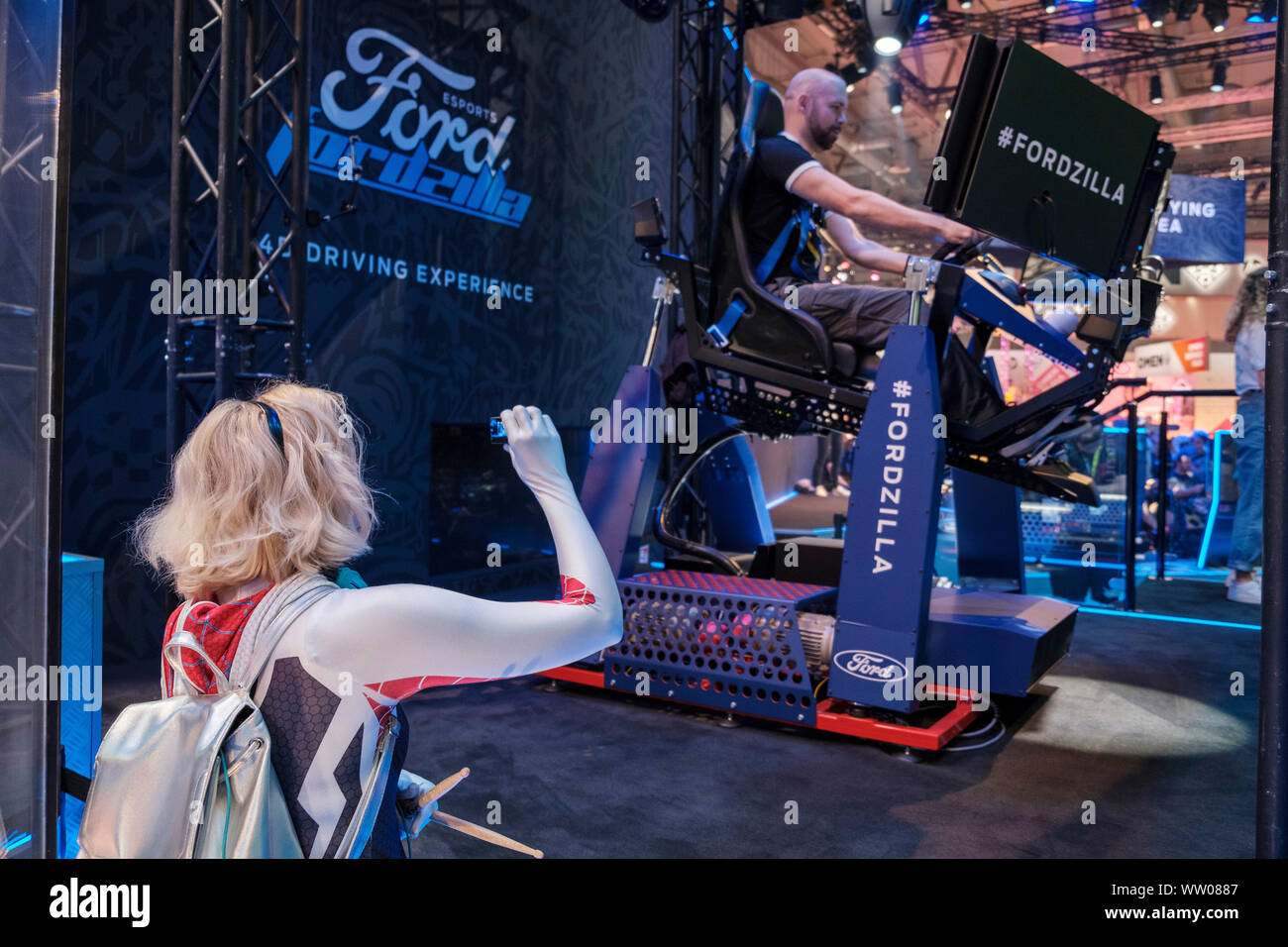 woman in cosplay costume takes picture of man in car racing simulator ...