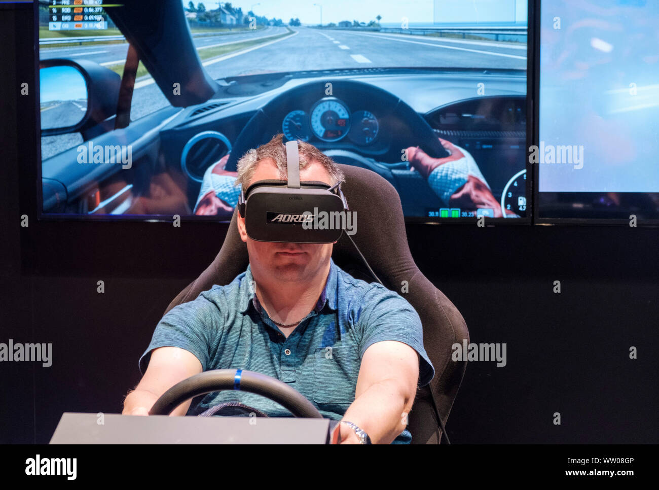 gamer wearing virtual reality headset in car race simulator at gamescom ...