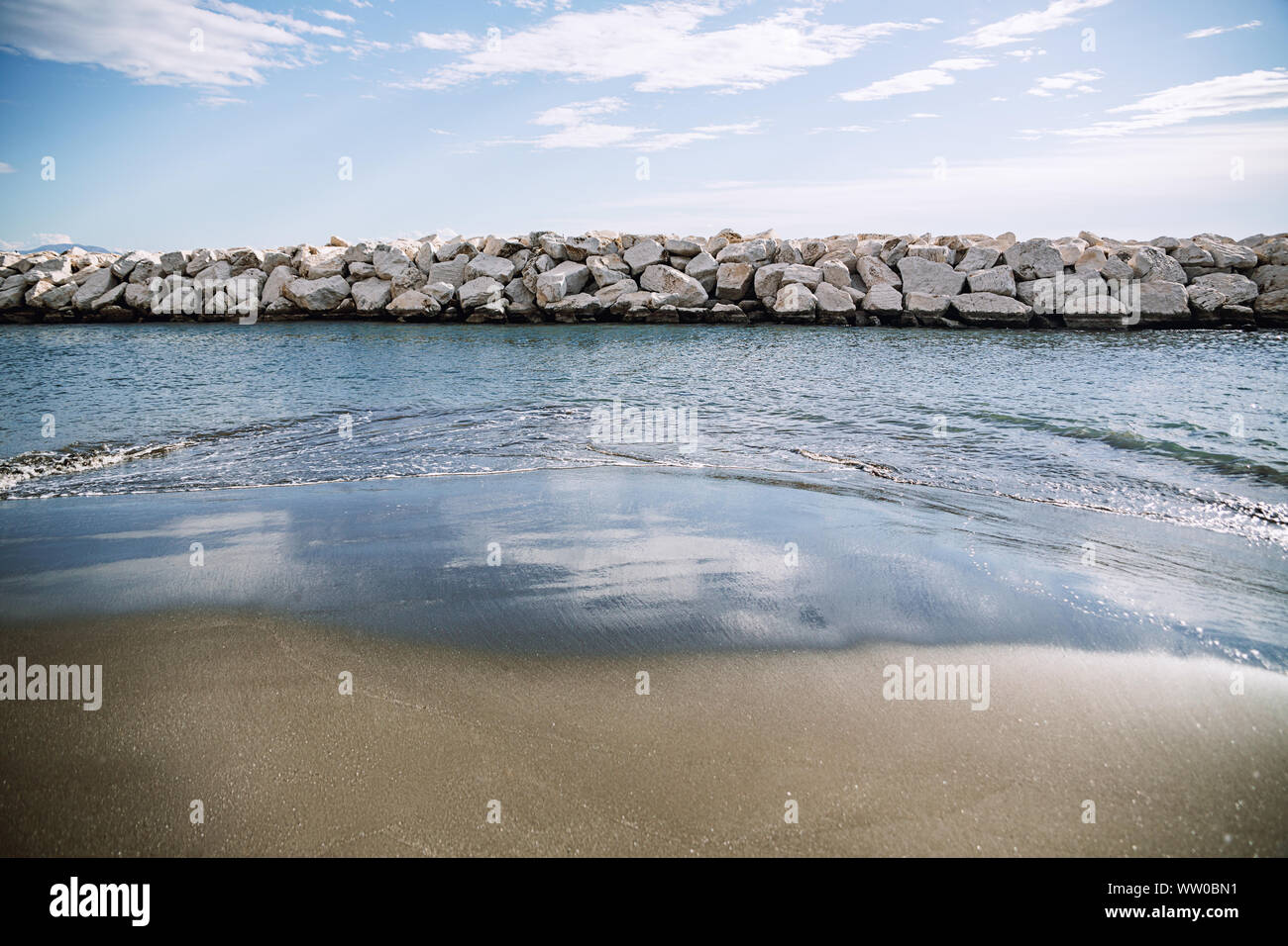 Beautiful stone wall separating the sea. waves pour in around rocks on ...