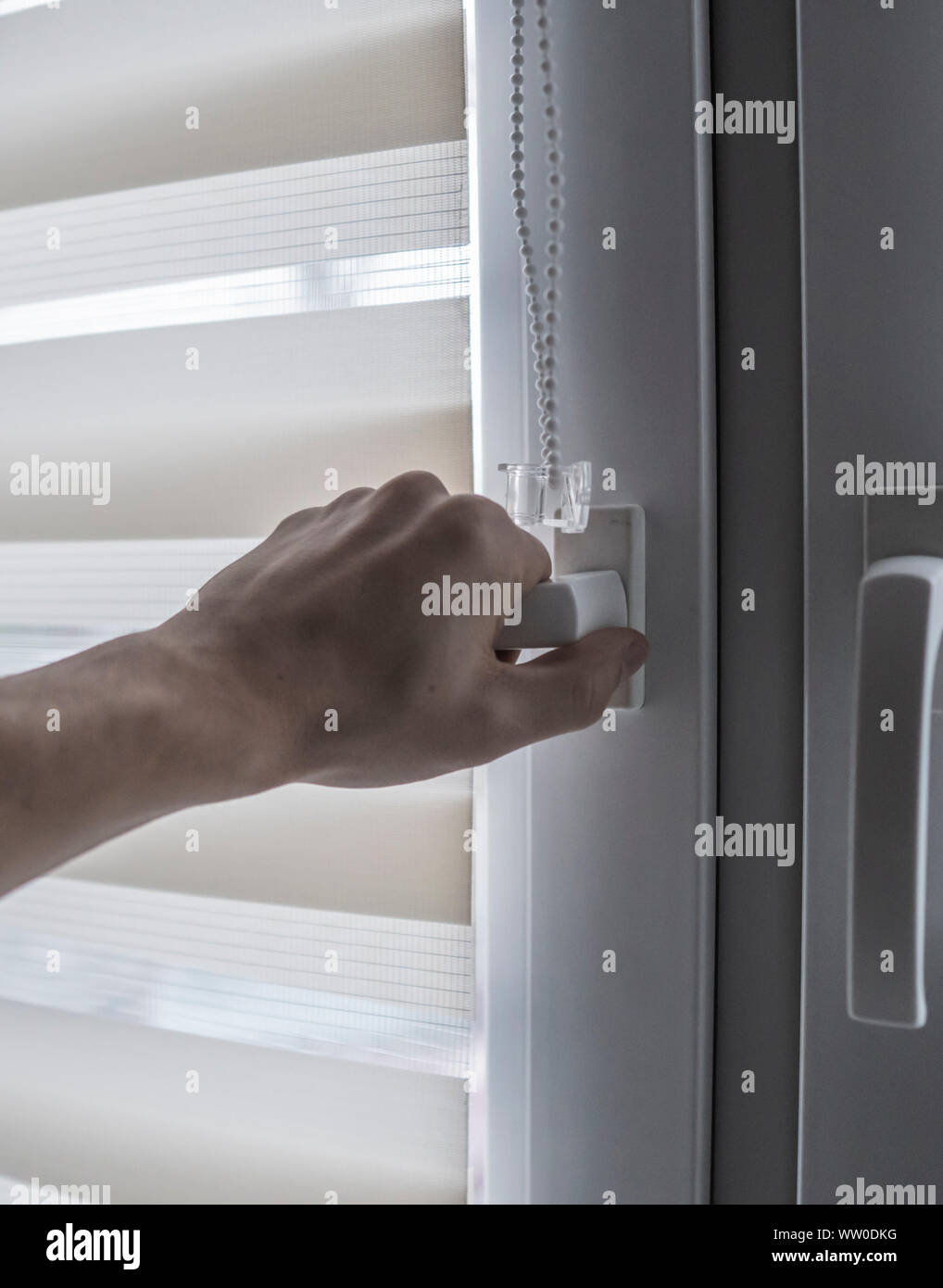 Man holding window handle on a plastic window with white fabric roller ...