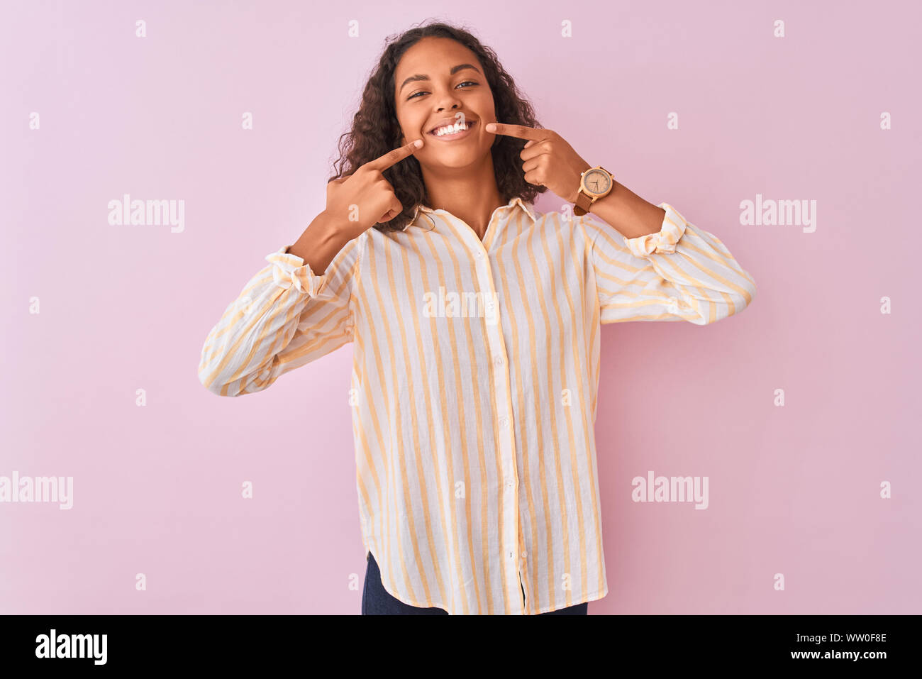Young Brazilian Woman Wearing Striped Shirt Standing Over Isolated Pink