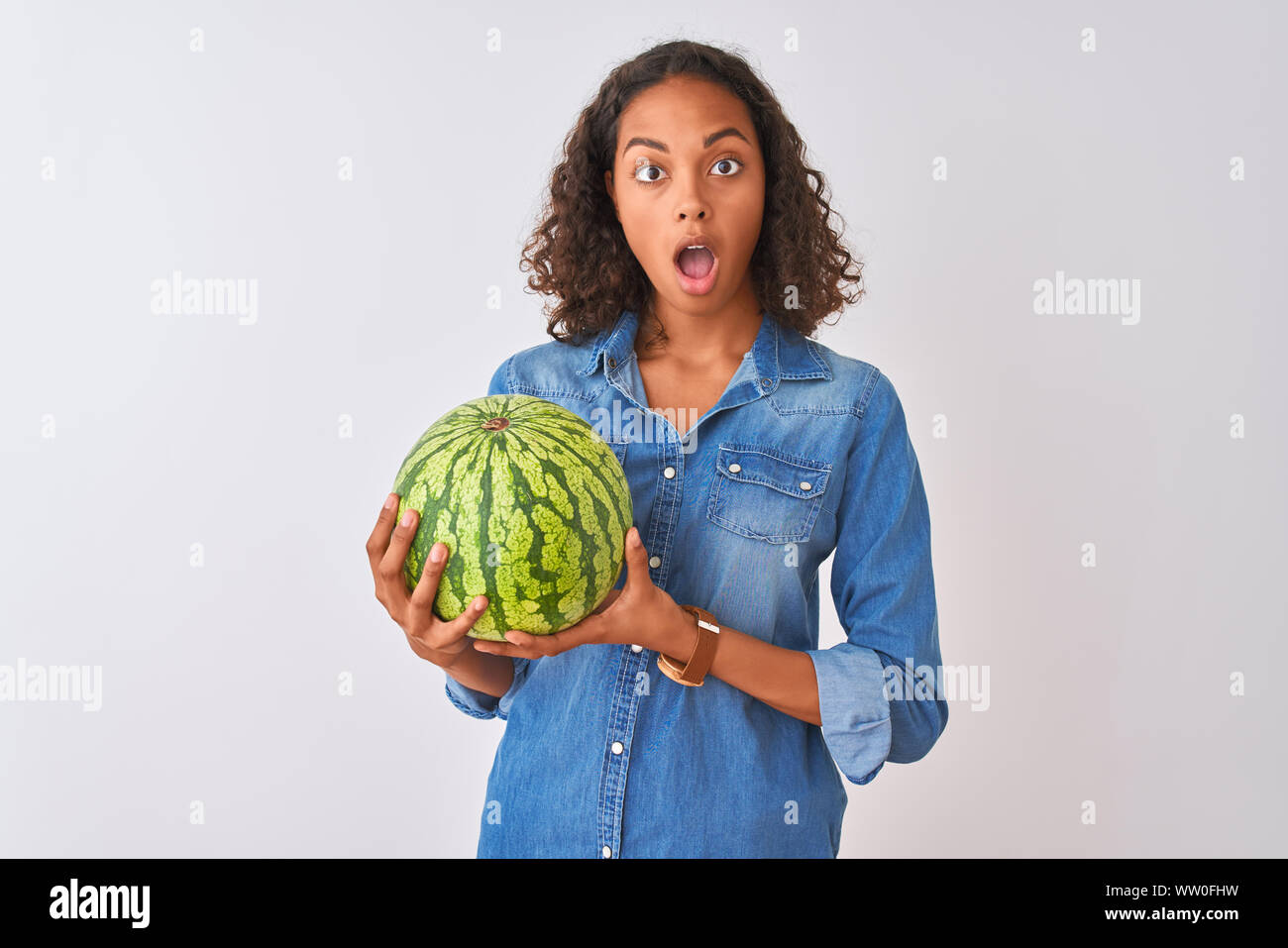 Young brazilian woman holding watermelon standing over isolated white ...