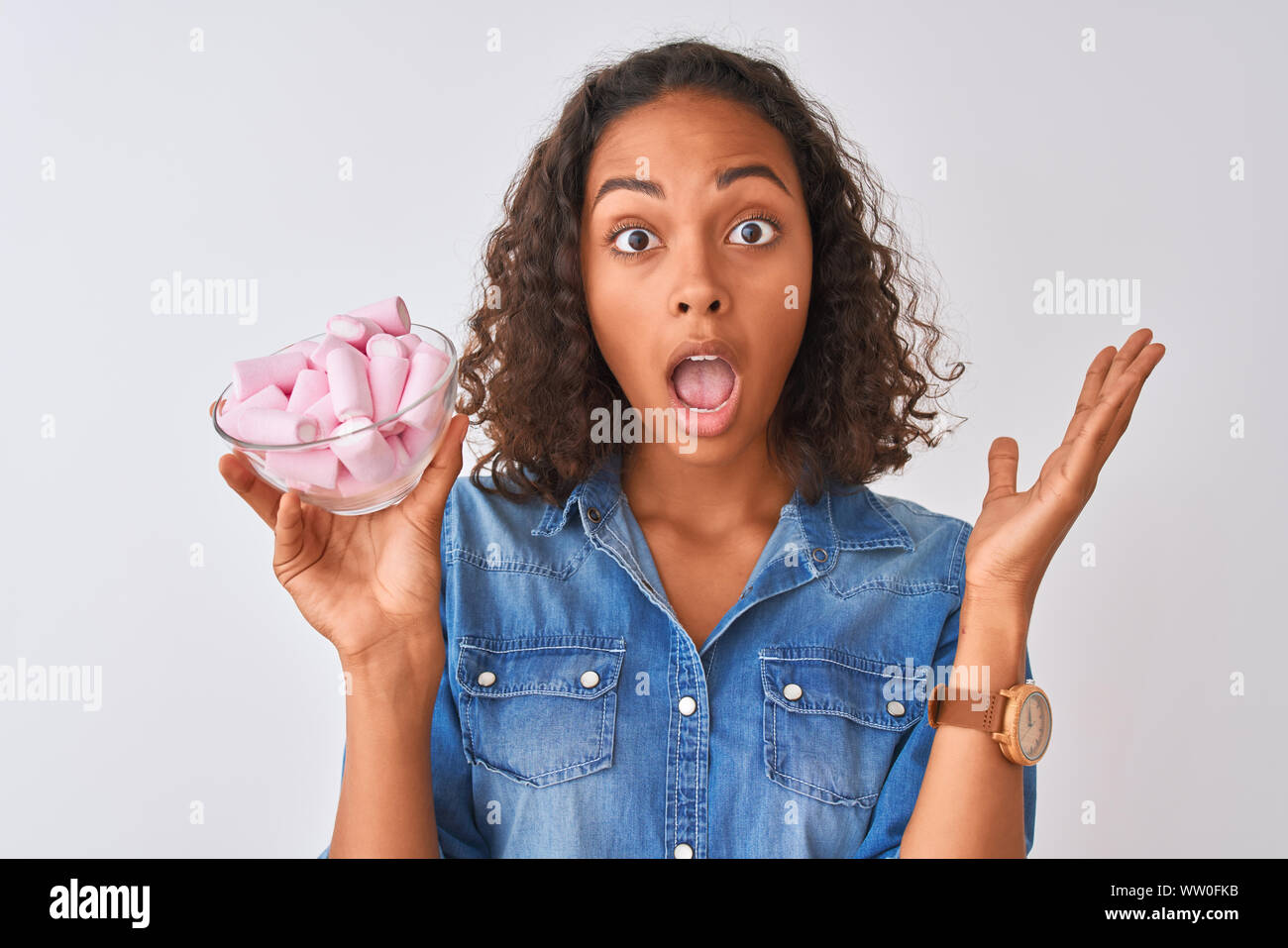 Young brazilian woman holding bowl with marshmallows over isolated ...
