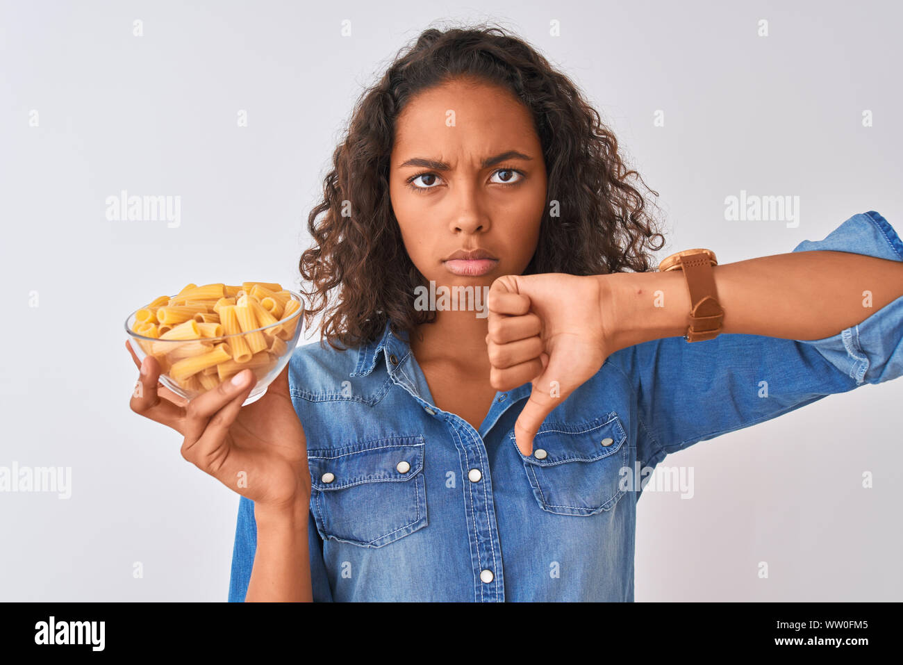 Young brazilian woman holding bowl with macaroni pasta over isolated ...