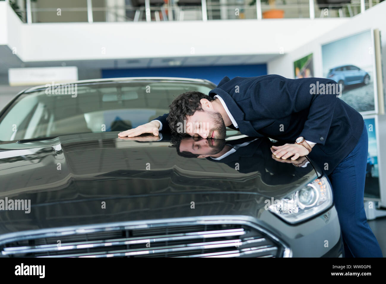 Handsome young man in classic blue suit is smiling while examining car ...