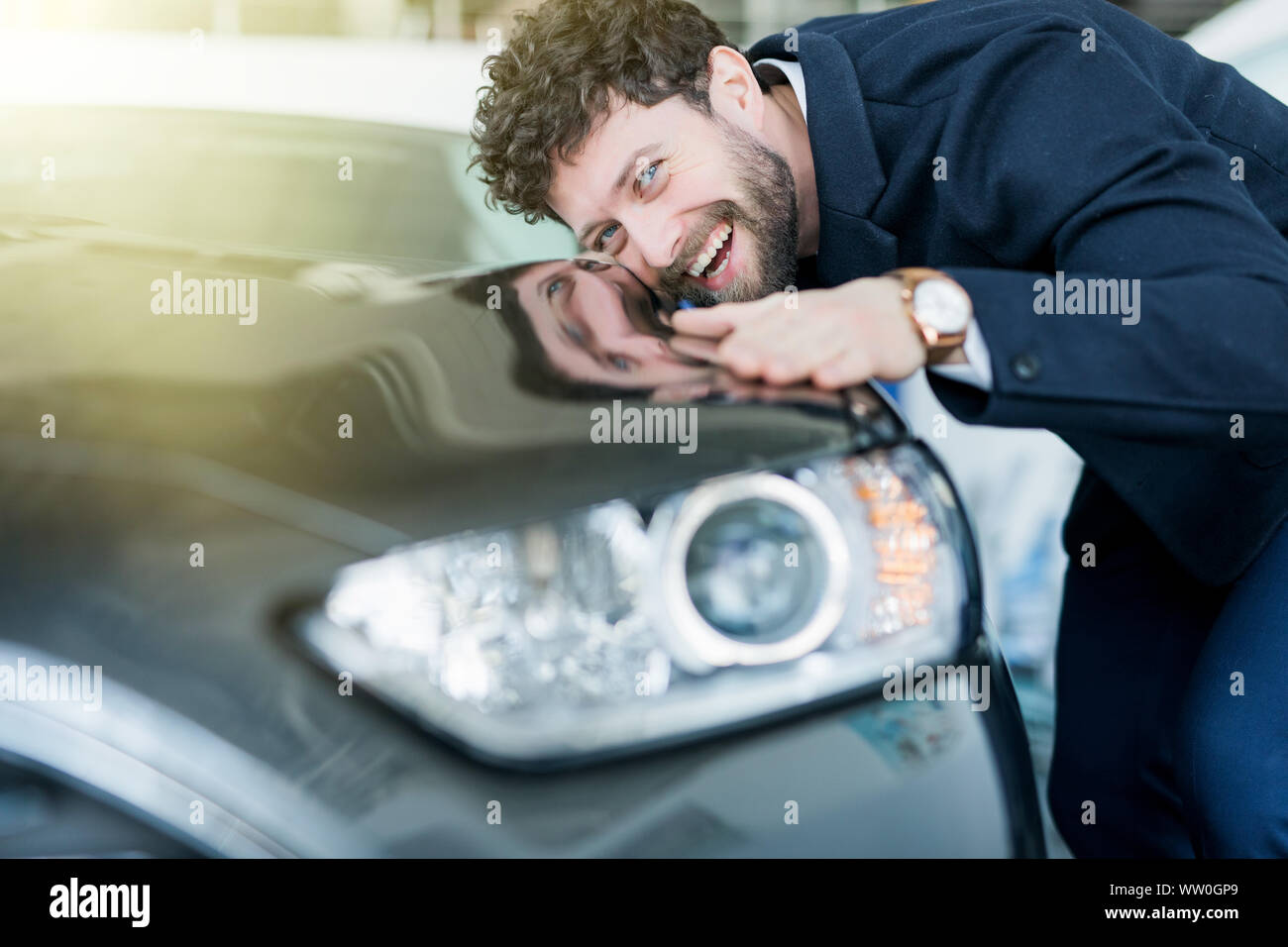 Handsome young man in classic blue suit is smiling while examining car ...
