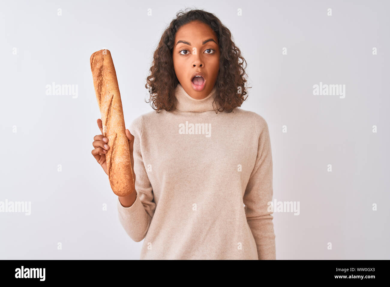Young brazilian baker woman holding bread standing over isolated white ...