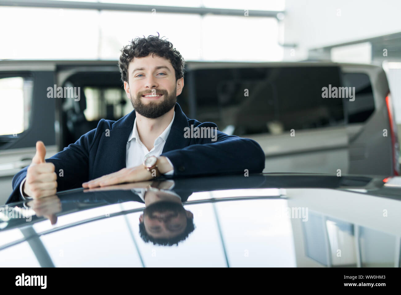 Cheerful car salesman smiling showing thumbs up posing at the ...