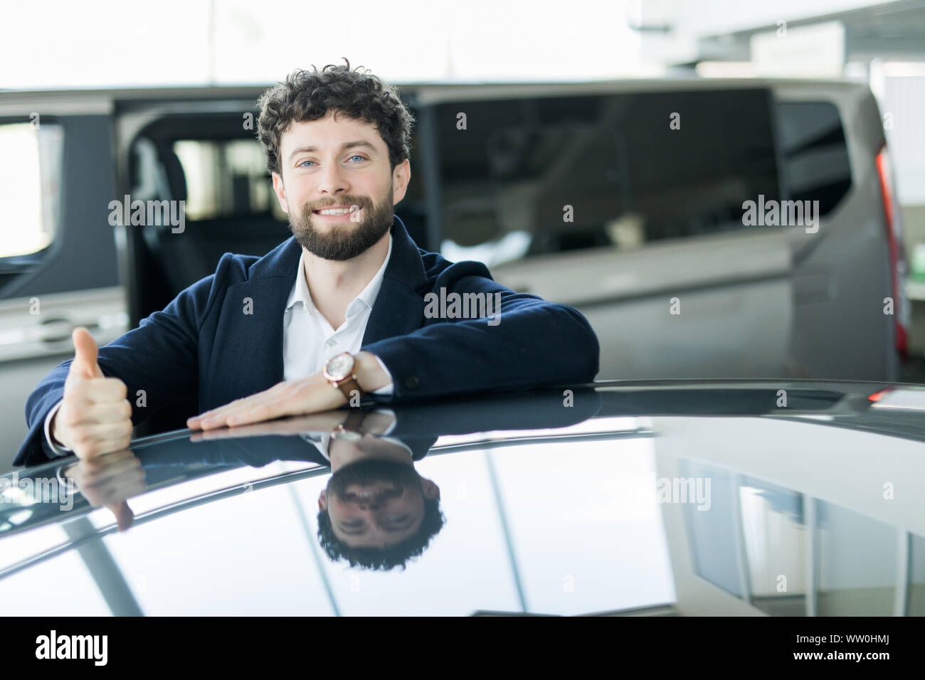 Cheerful car salesman smiling showing thumbs up posing at the ...