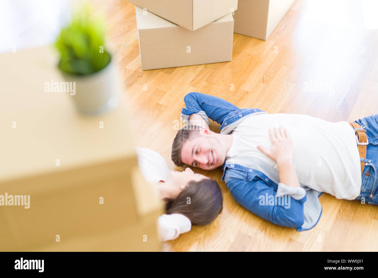 Young beautiful couple relaxing lying on the floor around cardboard ...