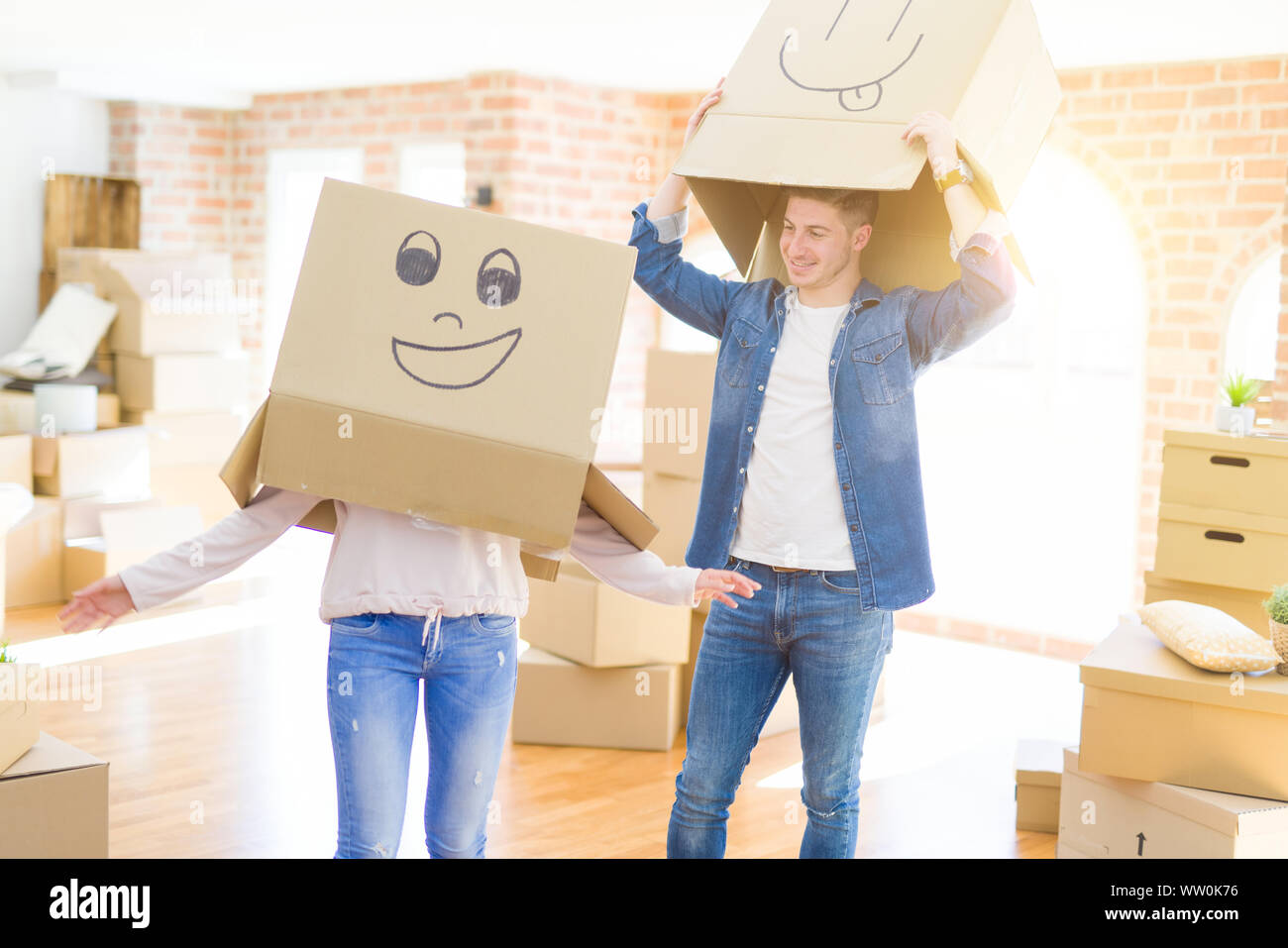 Couple having fun at new apartment wearing boxes with funny faces over ...
